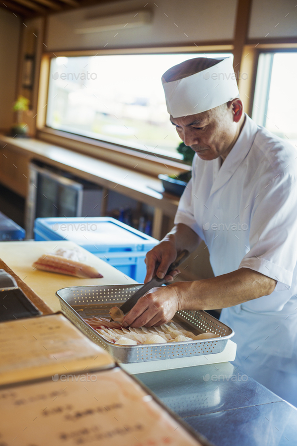 Chef working at a counter at a Japanese sushi restaurant, preparing ...