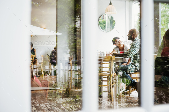 View through a window into a cafe, people sitting at tables. Stock ...