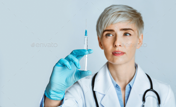 Nurse makes injection. Woman in white coat with medical gloves looks at ...