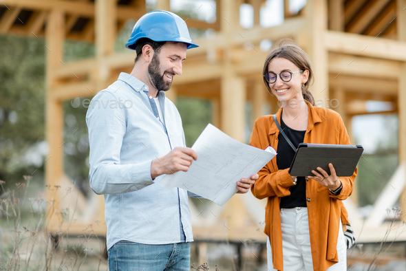 Builder with a female client on the construction site Stock Photo by ...