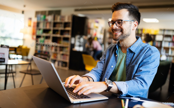 Smiling male student working and studying in a library Stock Photo by ...