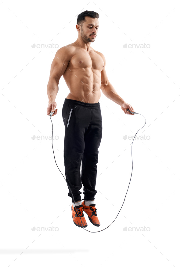 Shirtless bodybuilder jumping using rope Stock Photo by serhiibobyk