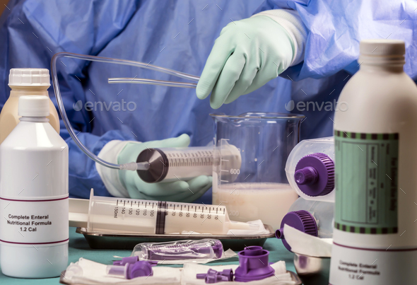 Nurse extracts enteral nutrition content with syringe, pailative care ...