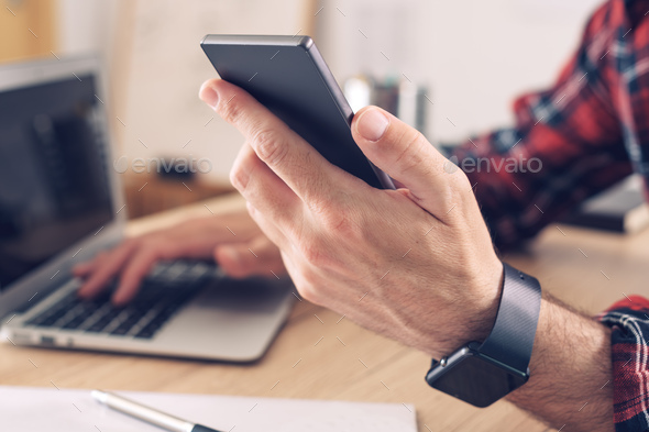 Using smart phone and laptop computer in home office Stock Photo by ...
