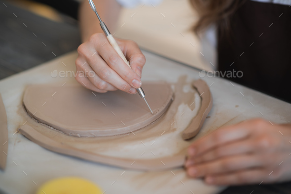 Close-up of a master potter, clay cutting special tool. Female artist ...
