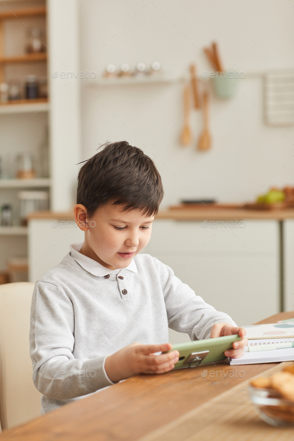Cute Boy Playing Mobile Game while Studying Stock Photo by ...