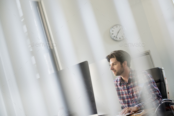 View through an office partition of a man seated at a desk. Stock Photo ...