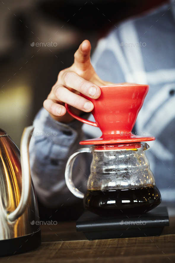 Specialist coffee shop. A man brewing coffee using a filter paper, and ...