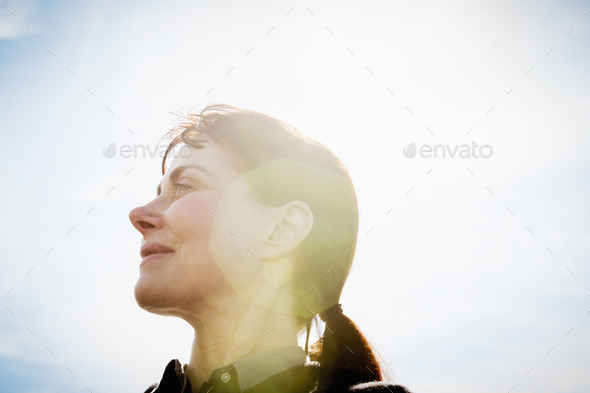 A woman, low angle view, side profile, looking upwards. Lens flare ...