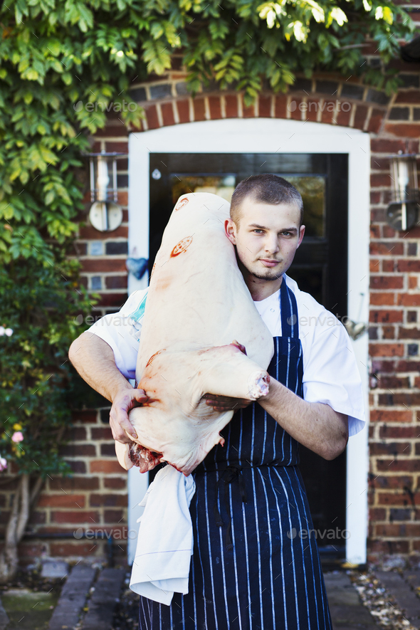 Chef of The Red Lion village public house carrying an animal carcass ...