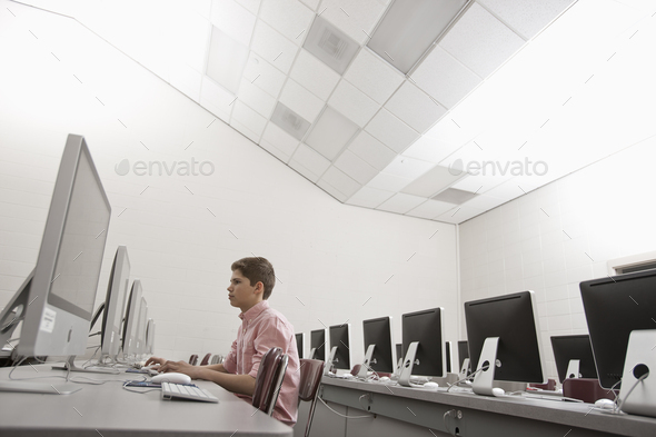 A school room, a computer lab with rows of screens, one teenager ...