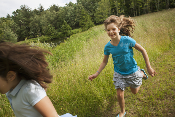 Two children, girls playing chase and running along a path. Stock Photo ...