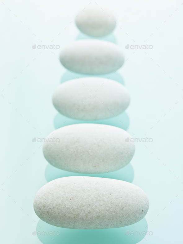Smooth white pebbles of uniform size and colour displayed on a blue ...