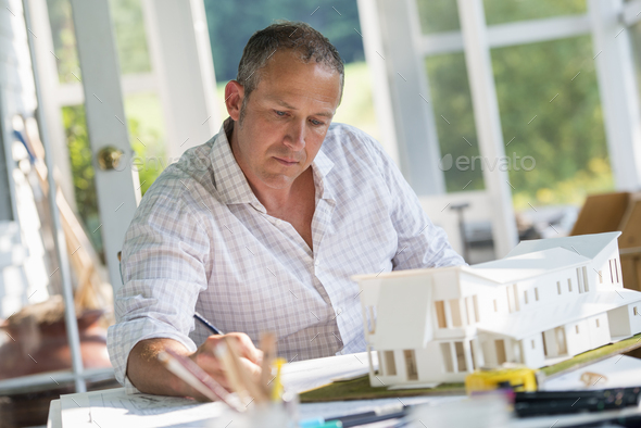 A man using a pencil drawing on an architect's plan, redesigning and ...