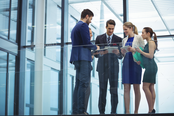 Business executives using electronic devices in corridor Stock Photo by ...
