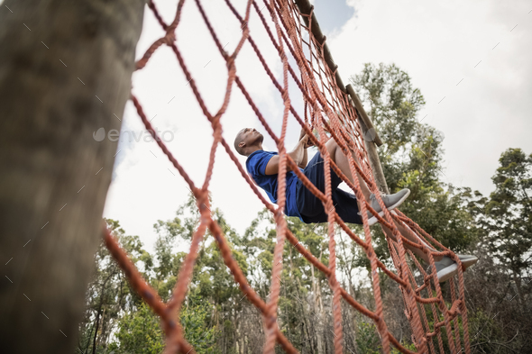 Fit man climbing a net during obstacle course Stock Photo by Wavebreakmedia