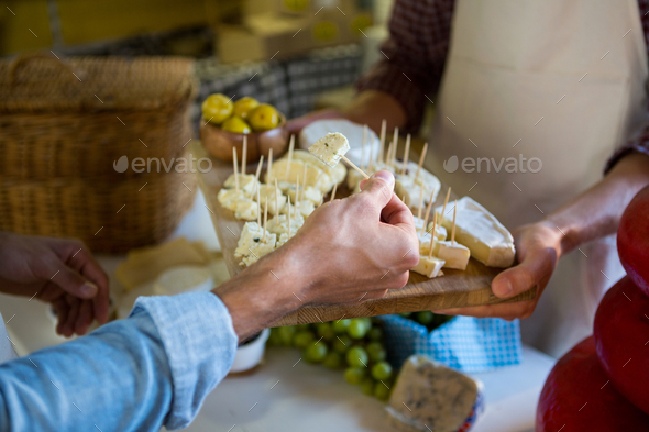 Staff showing a sample of cheese to customer at counter Stock Photo by ...
