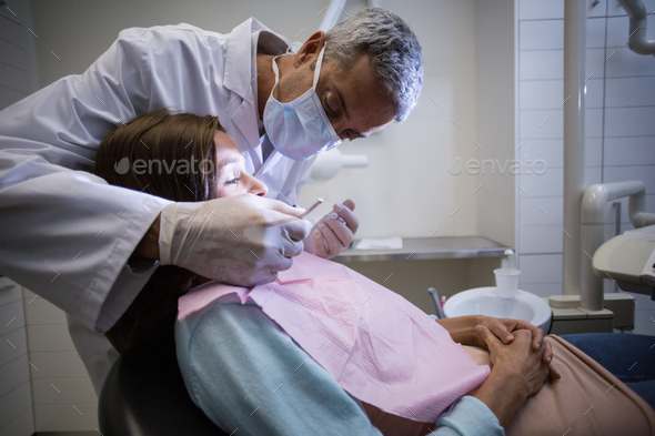 Dentist examining a female patient with tools Stock Photo by Wavebreakmedia