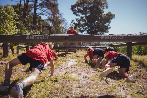 Kids crawling under the net during obstacle course training Stock Photo ...