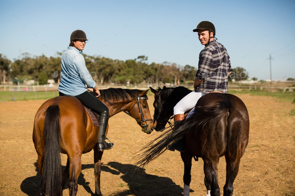 Two male friends riding horse in the ranch Stock Photo by Wavebreakmedia