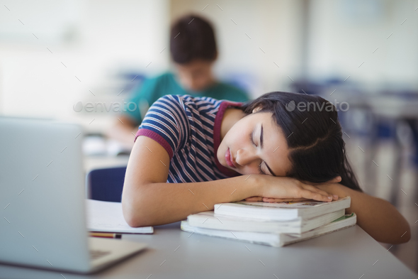 Tired schoolgirl sleeping in classroom Stock Photo by Wavebreakmedia