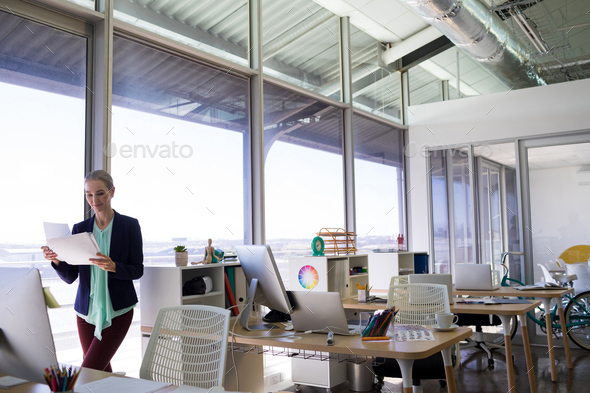 Female executive reading document at her desk Stock Photo by Wavebreakmedia