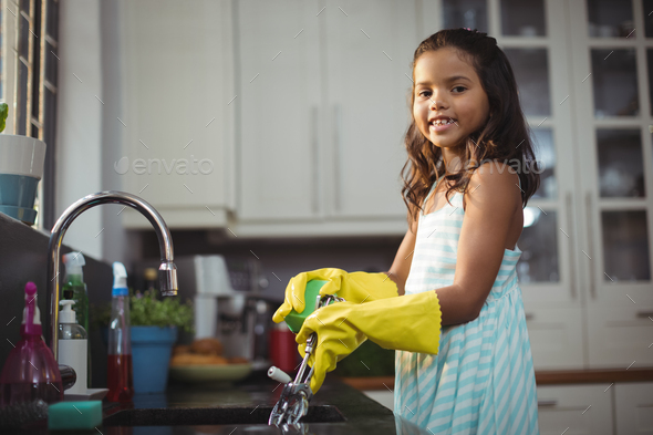 Cute little girl washing utensil in kitchen sink Stock Photo by ...