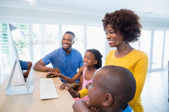 Happy family using computer in living room Stock Photo by Wavebreakmedia