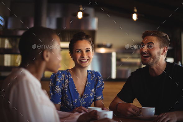 Happy friends interacting while having coffee Stock Photo by Wavebreakmedia
