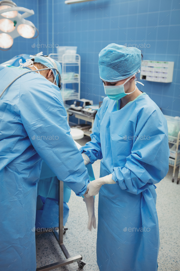 Nurse helping a surgeon in wearing surgical gloves Stock Photo by ...