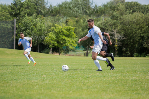 Football players playing soccer in the ground Stock Photo by Wavebreakmedia