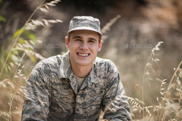 Portrait of happy military soldier crouching in grass Stock Photo by ...