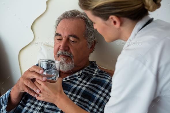 Side view of female doctor giving water to senior patient Stock Photo ...