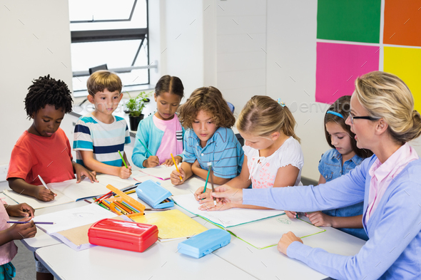 Teacher helping kids with their homework in classroom Stock Photo by ...