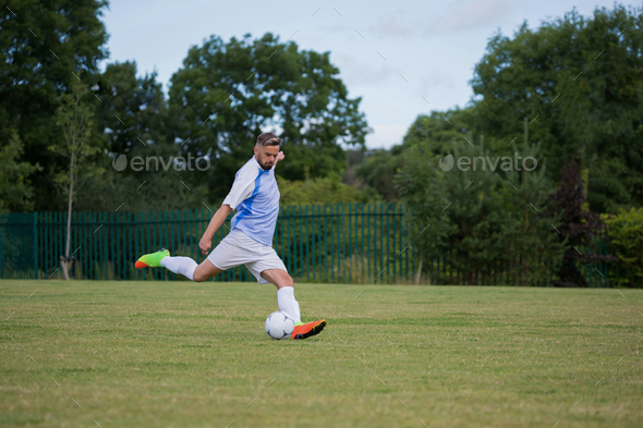 Football player kicking the soccer on the football ground Stock Photo ...