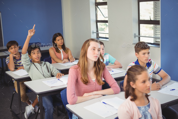 School kids raising hand in classroom Stock Photo by Wavebreakmedia