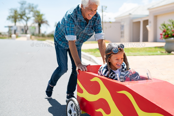 Grandfather pushing his little boy on toy car Stock Photo by Rido81