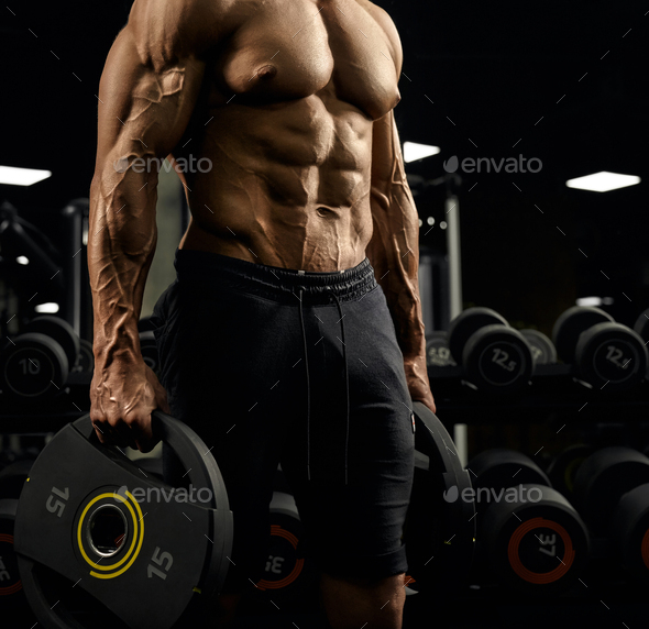 Tensed male bodybuilder holding weights Stock Photo by serhiibobyk