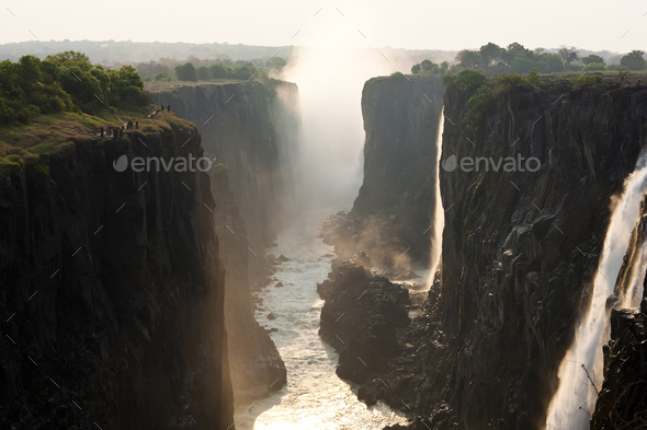 Wide and high waterfall cascading down steep rock wall of a gorge ...