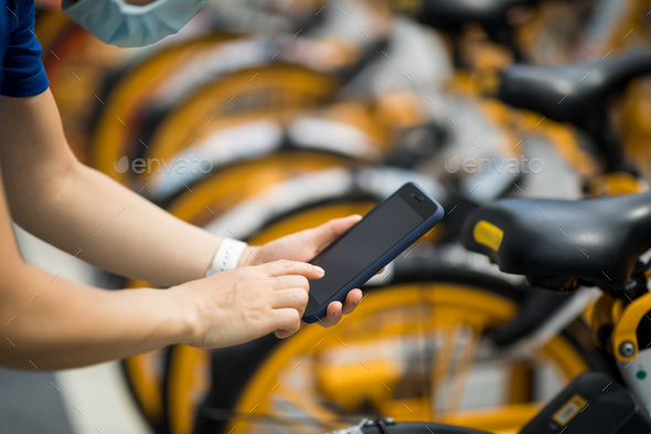 Hands using smartphone scanning the QR code of shared bike in city ...