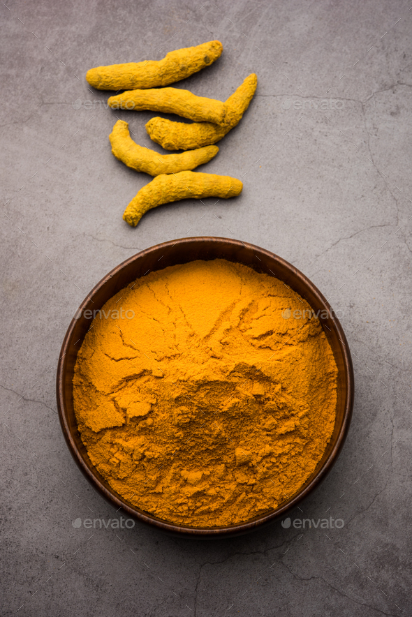 Organic Haldi or Turmeric powder spice pile in a bowl with whole ...