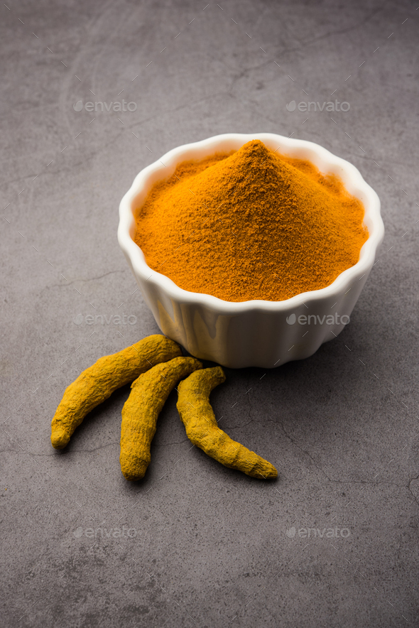 Organic Haldi or Turmeric powder spice pile in a bowl with whole ...