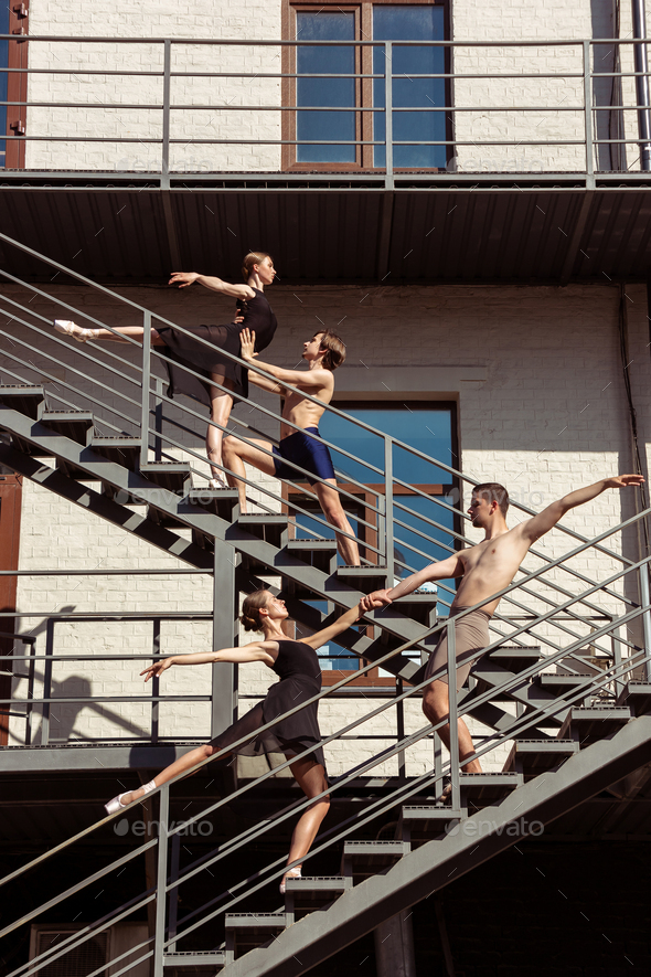 The group of modern ballet dancers performing on the stairs at the city ...