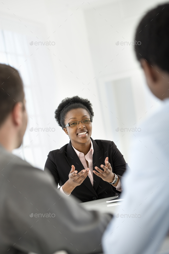Three people sitting around a table at a business meeting. Stock Photo ...