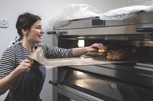 Artisan bakery making special sourdough bread, baker removing a tray of ...