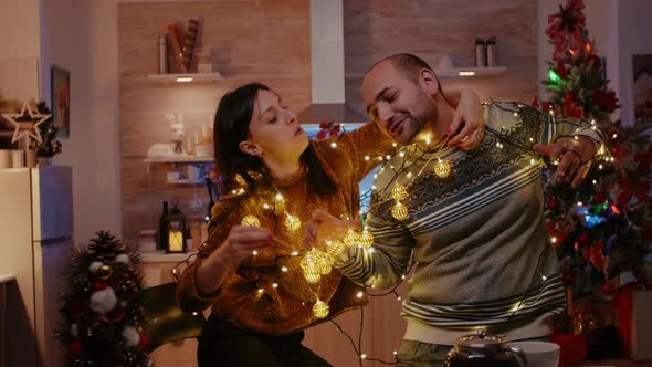 Cheerful Couple Getting Tangled in String of Twinkle Lights, Stock Footage