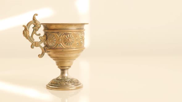 Holly grail look like ancient object made of brass on white reflective ...