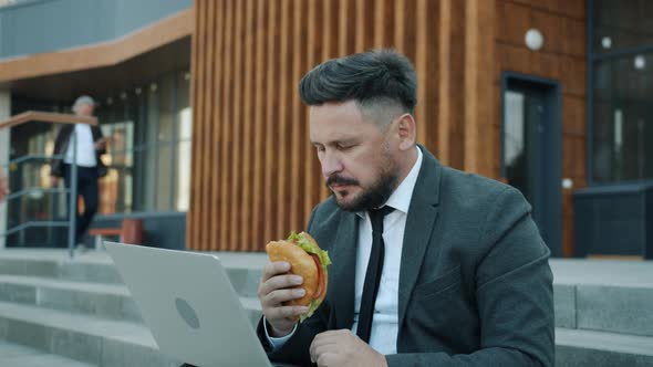 Portrait of Middleaged Manager Eating Sandwich and Using Laptop Sitting ...
