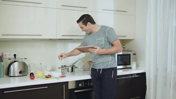 Happy Man Cooking Healthy Dinner at Kitchen. Smiling Person Reading ...