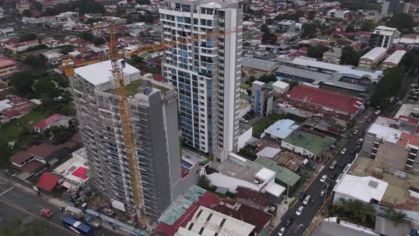 Cinematic aerial shot of a tower crane constructing a skyscraper in ...